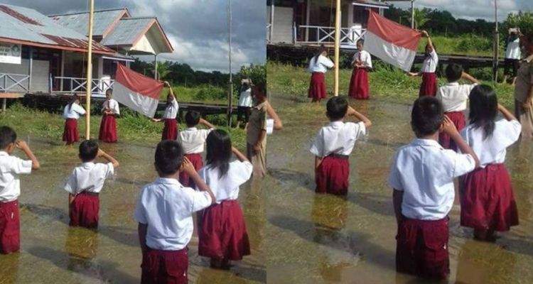 Siswa-siswa SD ini khidmat upacara bendera di tengah banjir